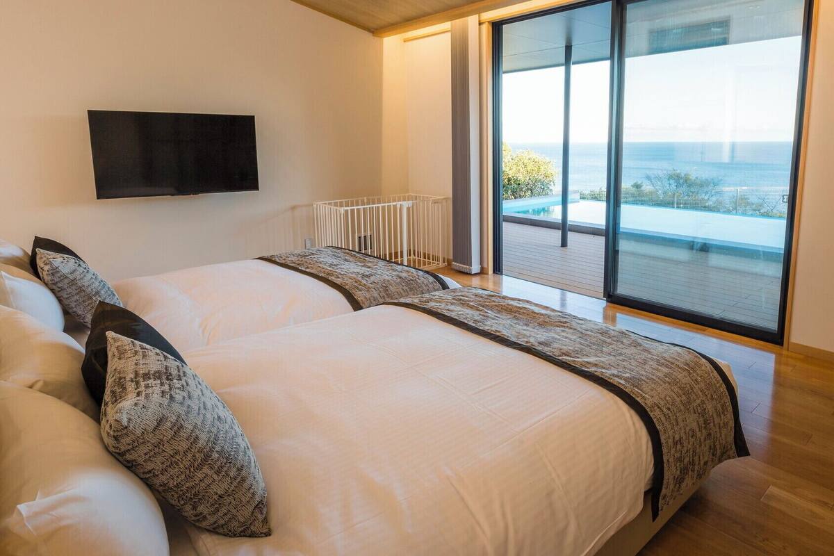 Quarto moderno com cama grande, televisão e vista para o mar.