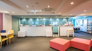 Um hall de hotel moderno com balcão de recepção, área de estar e espaço de recreação infantil.