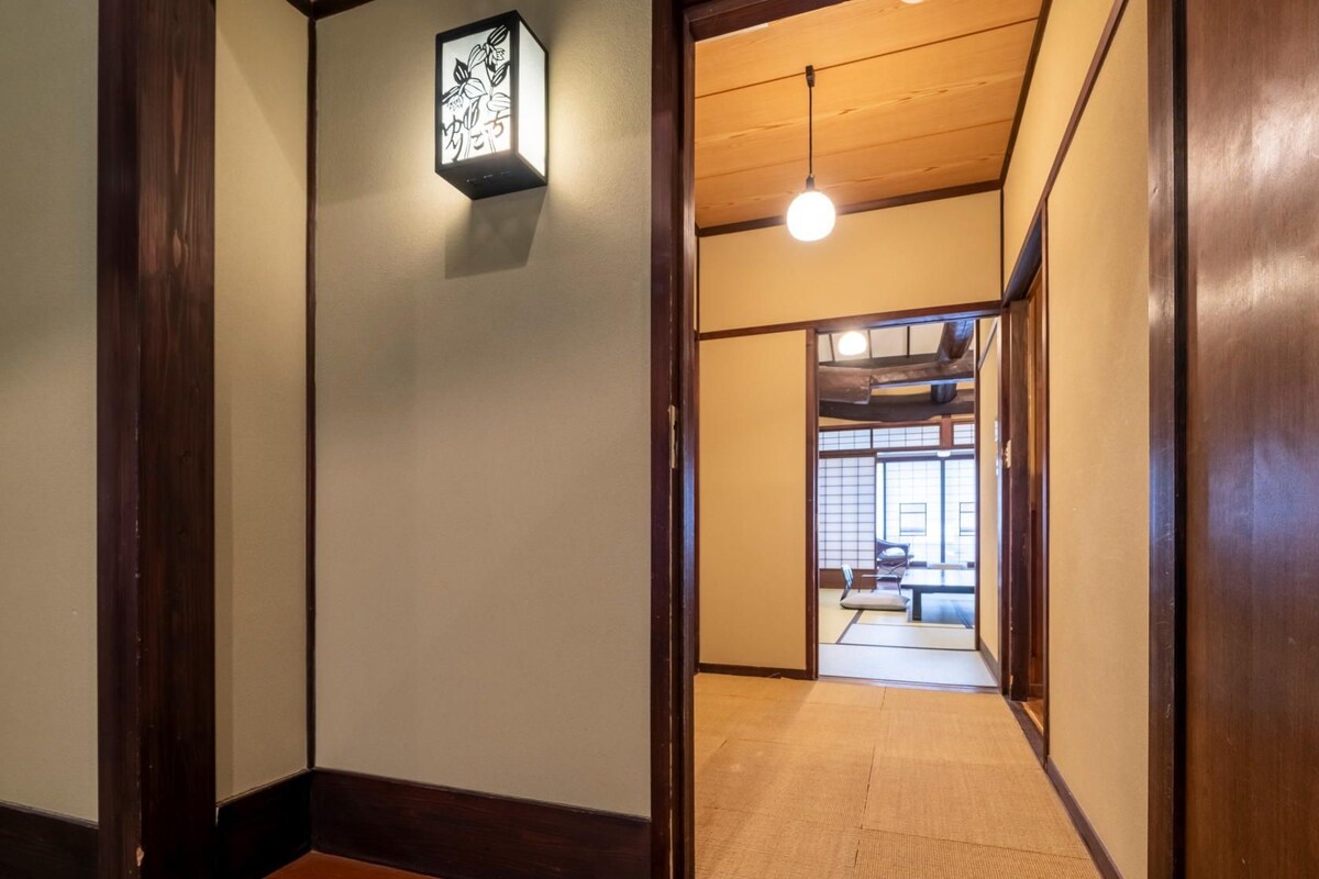 Um interior japonês tradicional com soalho de tatami, portas de correr e um candeeiro suspenso.