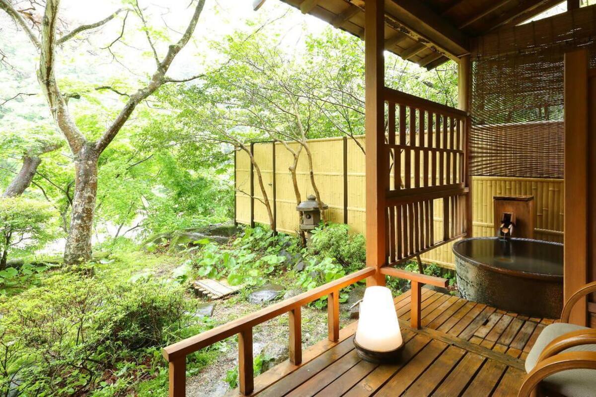 Um deck de madeira com uma nascente termal, um candeeiro e um quarto tradicional japonês.