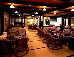 Quarto em estilo japonês tradicional, com tatames, mesas de madeira baixas e cadeiras estampadas.