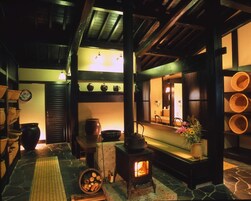 Interior tradicional com soalho de pedra, lareira a lenha e prateleiras com cerâmica.
