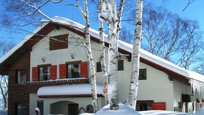 Uma casa de madeira de dois andares com telhado coberto de neve e varanda.
