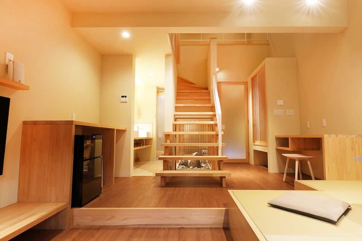 Interior moderno com escada de madeira, prateleiras embutidas e televisão de tela plana.