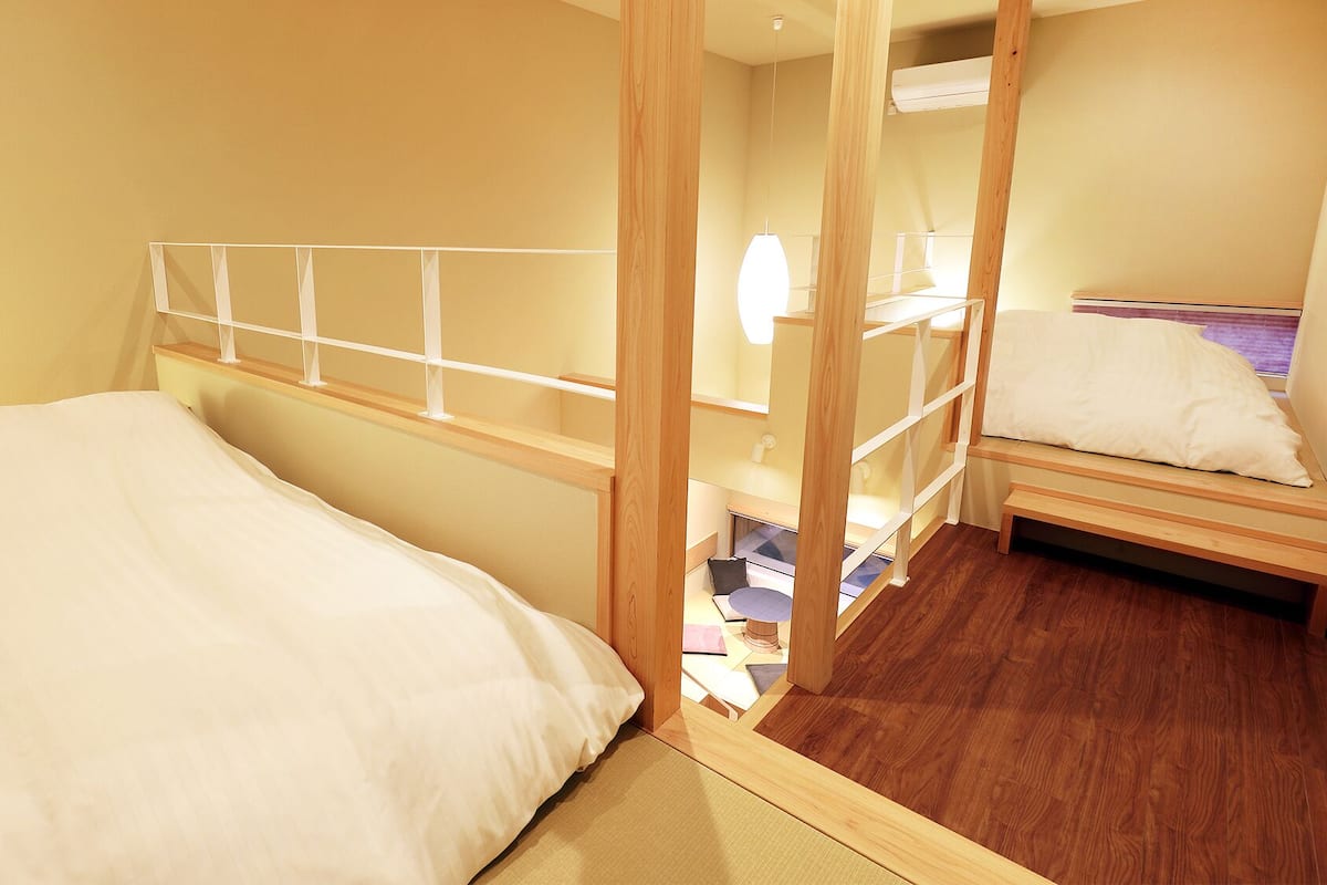 Uma cama de solteiro com cabeceira de madeira, mesa de cabeceira e uma cadeira pequena.