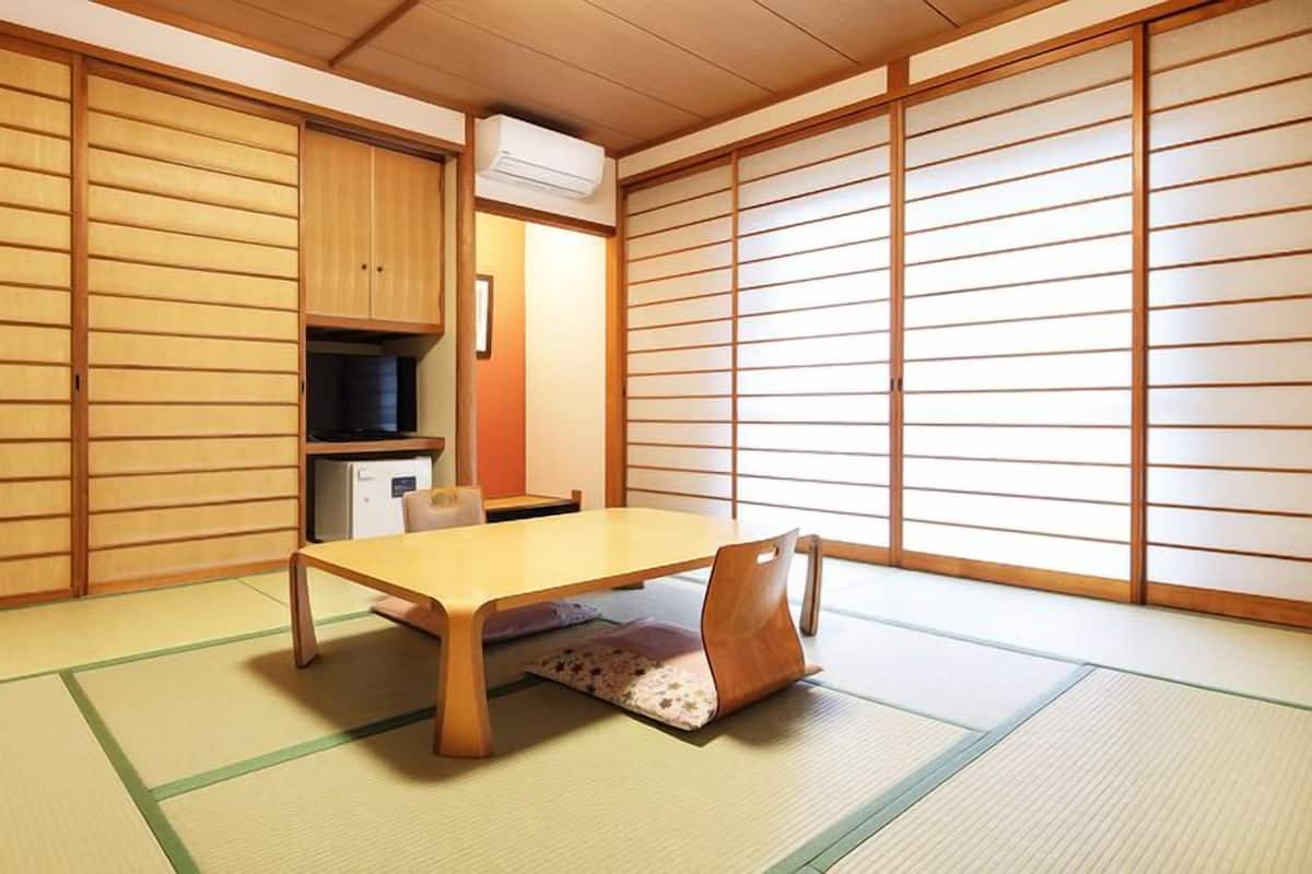 Um quarto japonês tradicional com tatames, uma mesa baixa e portas deslizantes.
