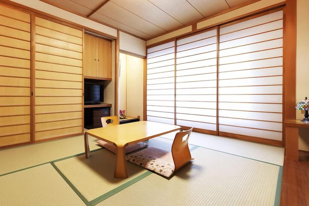 Um quarto japonês tradicional, com tatames, uma mesa baixa e portas deslizantes.