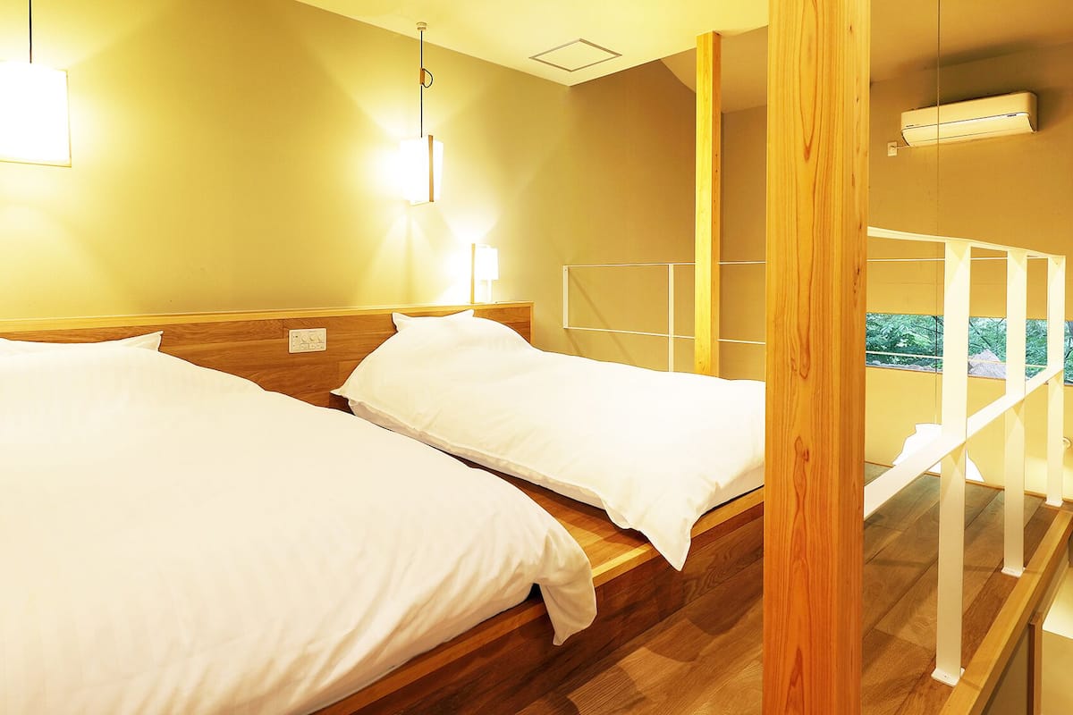 Quarto de hotel com duas camas, cabeceiras de madeira e varanda com vista.