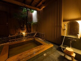 Uma onsen japonesa tradicional com um banco de madeira, um banquinho e uma banheira de pedra.
