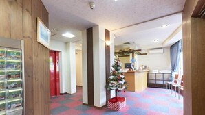 Um saguão de hotel com uma mesa de recepção, um pinheiro de Natal e uma área de estar.
