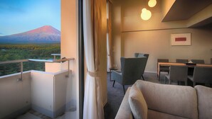 Quarto de hotel moderno com varanda e vista para uma montanha e floresta.