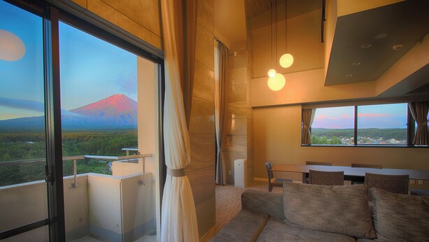 Quarto de hotel moderno com varanda, sofá e área de refeições.