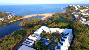 Vista aérea de uma área residencial costeira, com casas, praia e ampla visão do oceano.