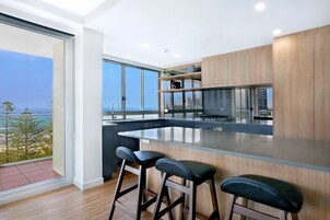 Uma cozinha moderna com uma ilha grande, banquetas de bar e vista para a cidade.