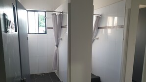 Uma casa de banho pequena e fechada, com zona de duche, janela e porta.