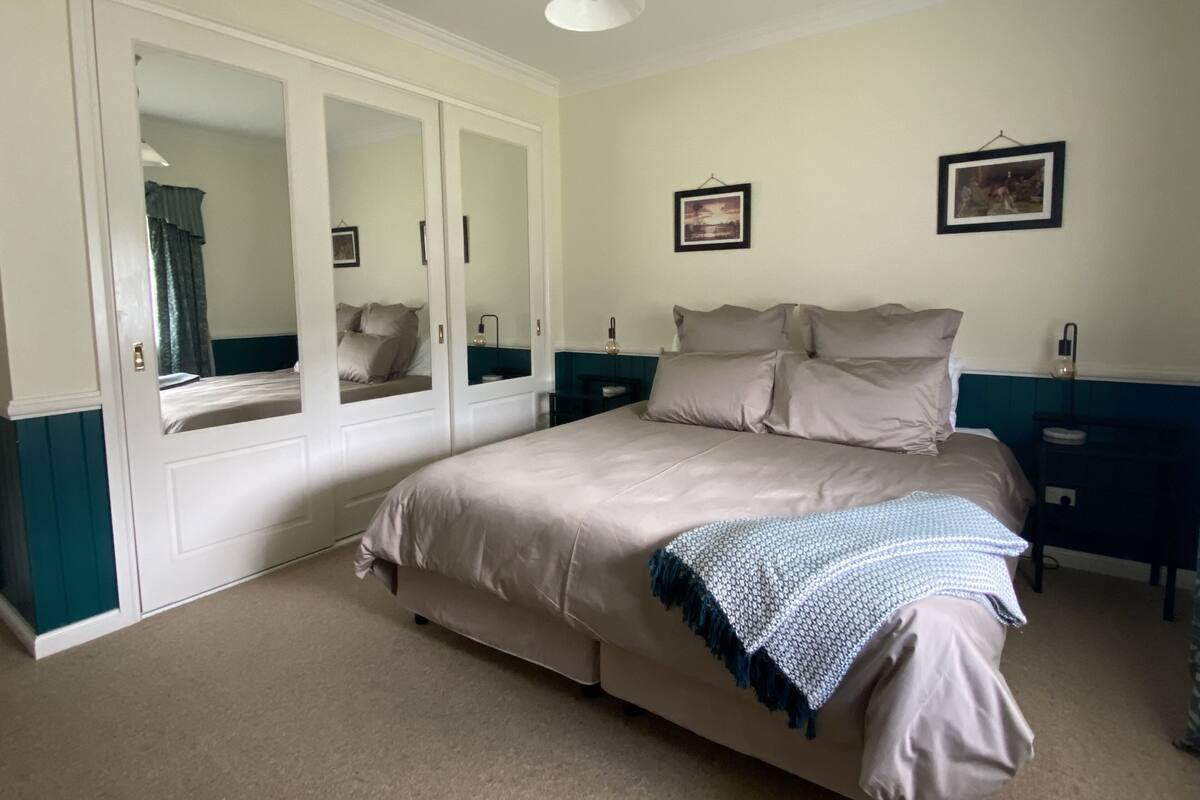 Quarto com cama, guarda-roupa, mesa de cabeceira e abajur.