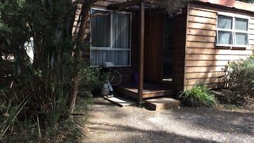 Uma pequena cabana de madeira com varanda, janela e porta.