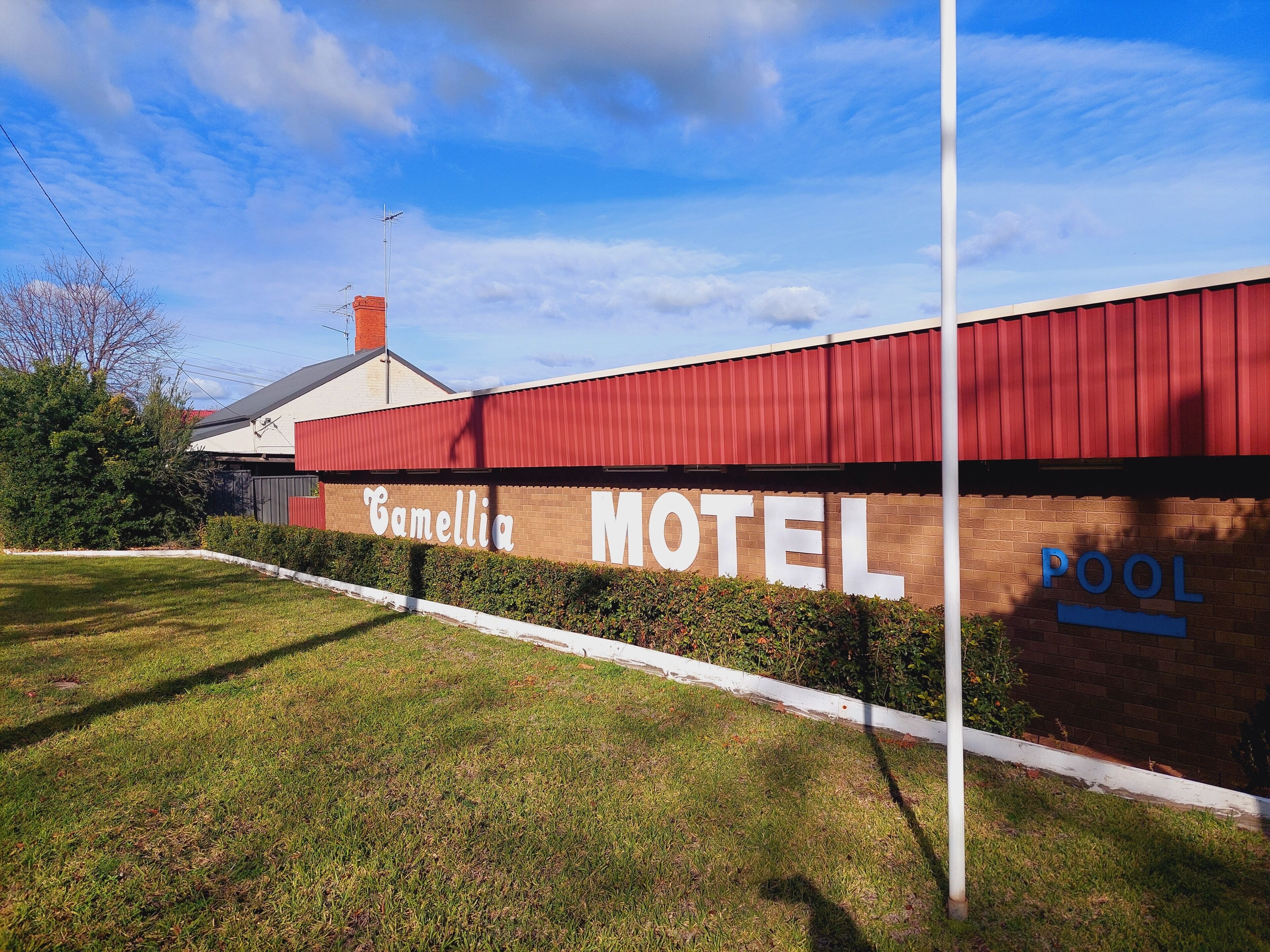 Um motel com fachada vermelha e uma placa que diz 'Camellia Motel'.