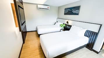 Quarto de hotel moderno com uma cama grande, uma mesinha de cabeceira, um ar condicionado e uma obra de arte emoldurada na parede.