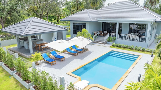 Uma casa moderna com piscina, área de estar externa e um terraço coberto.