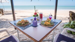 Uma mesa à beira-mar com comida e bebidas, com vista para o oceano.