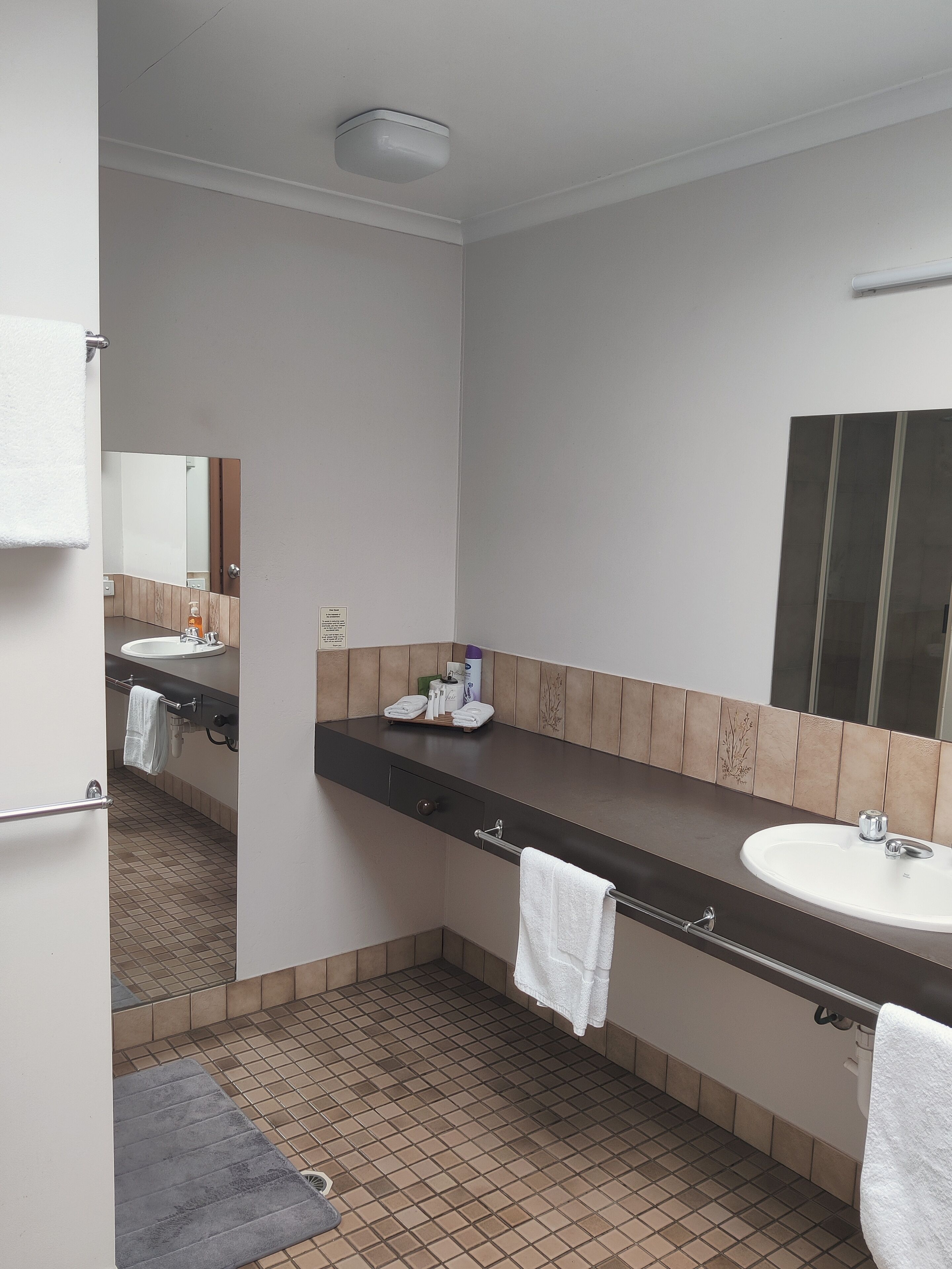 Um banheiro moderno com duas pias, um espelho e um porta-toalhas.