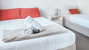 Quarto com cama, mesa de cabeceira, abajur e teto com vigas de madeira.