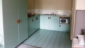 Cozinha compacta com armários verde-água, micro-ondas e unidade de ar condicionado na parede.