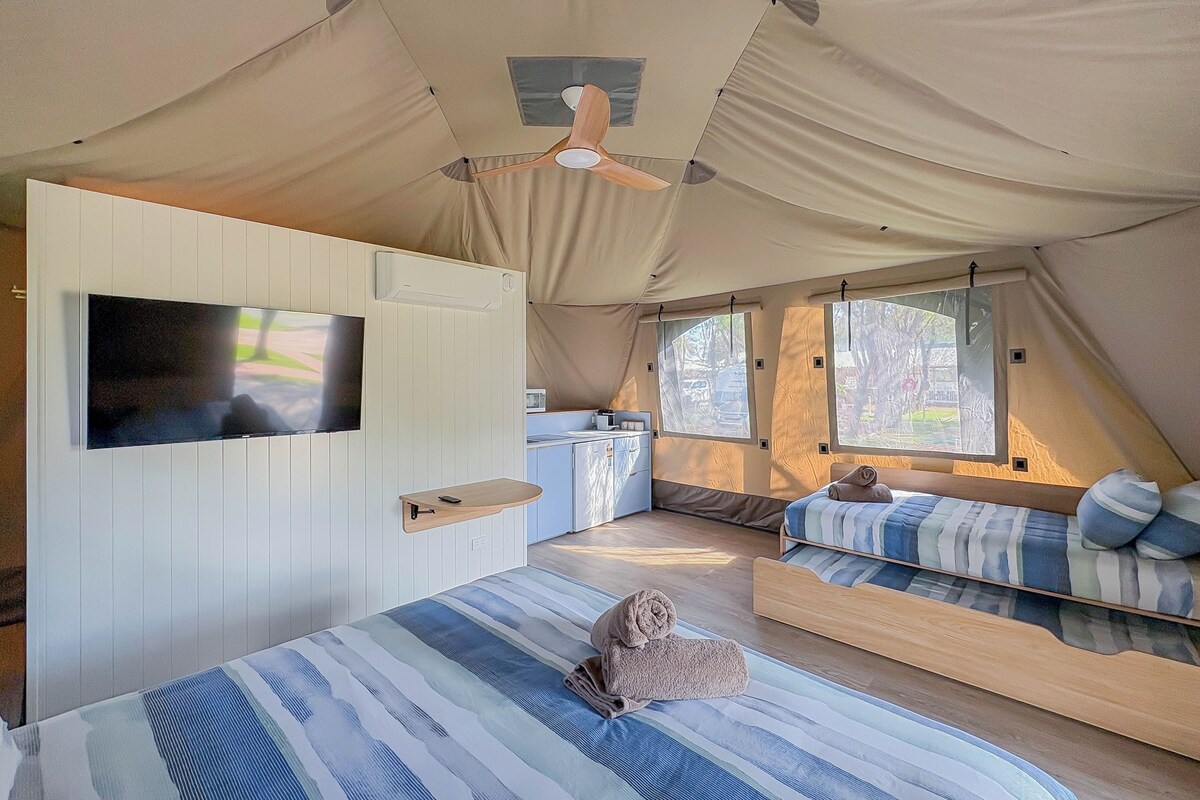 Acomodação em tenda com televisão, uma pequena cozinha e uma cama com vista.