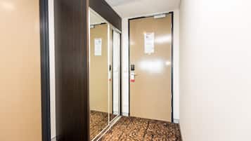 Um corredor com uma porta, um espelho e um tapete estampado.