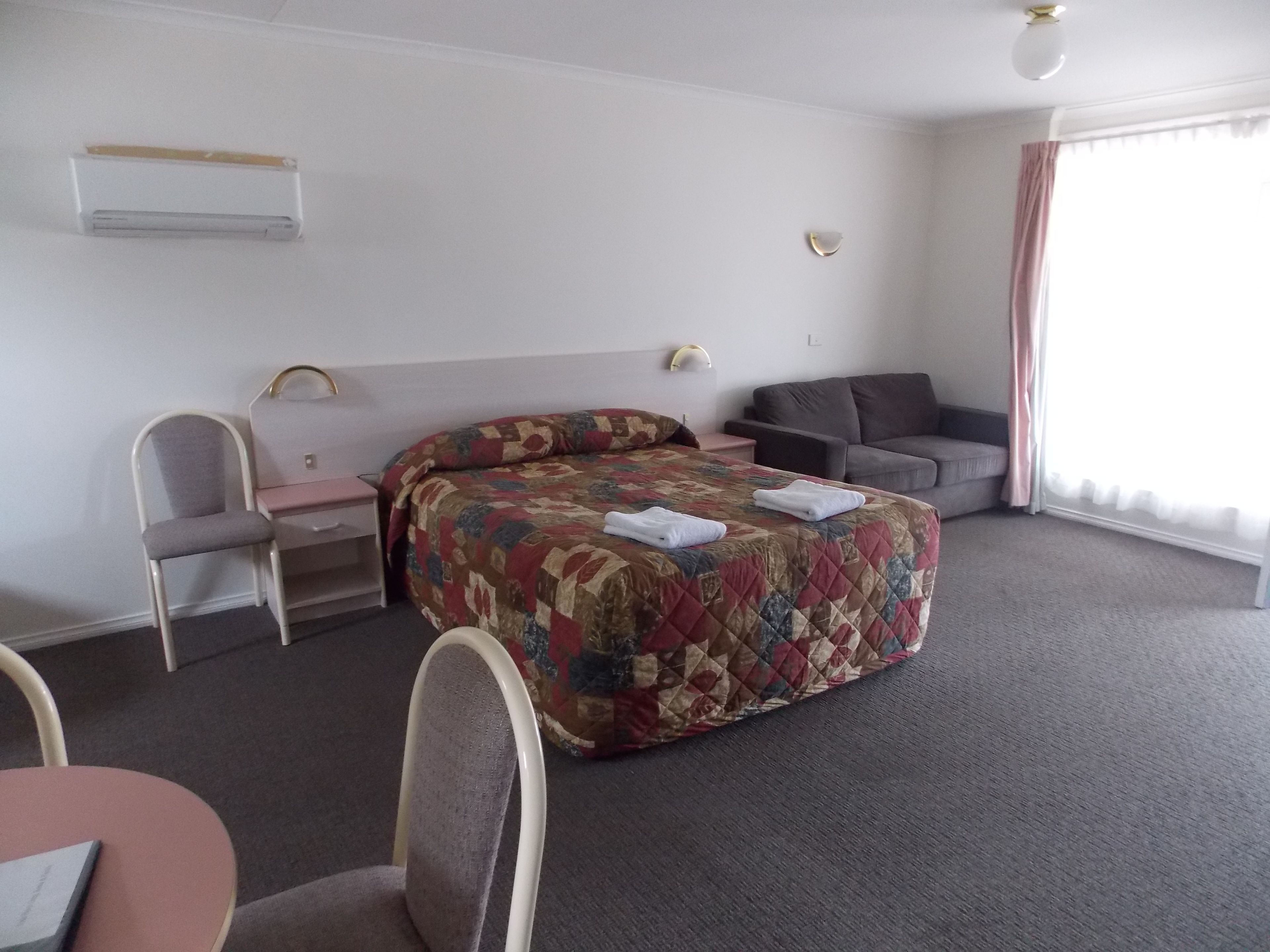 Quarto de hotel com cama, escrivaninha, cadeira e sofá.