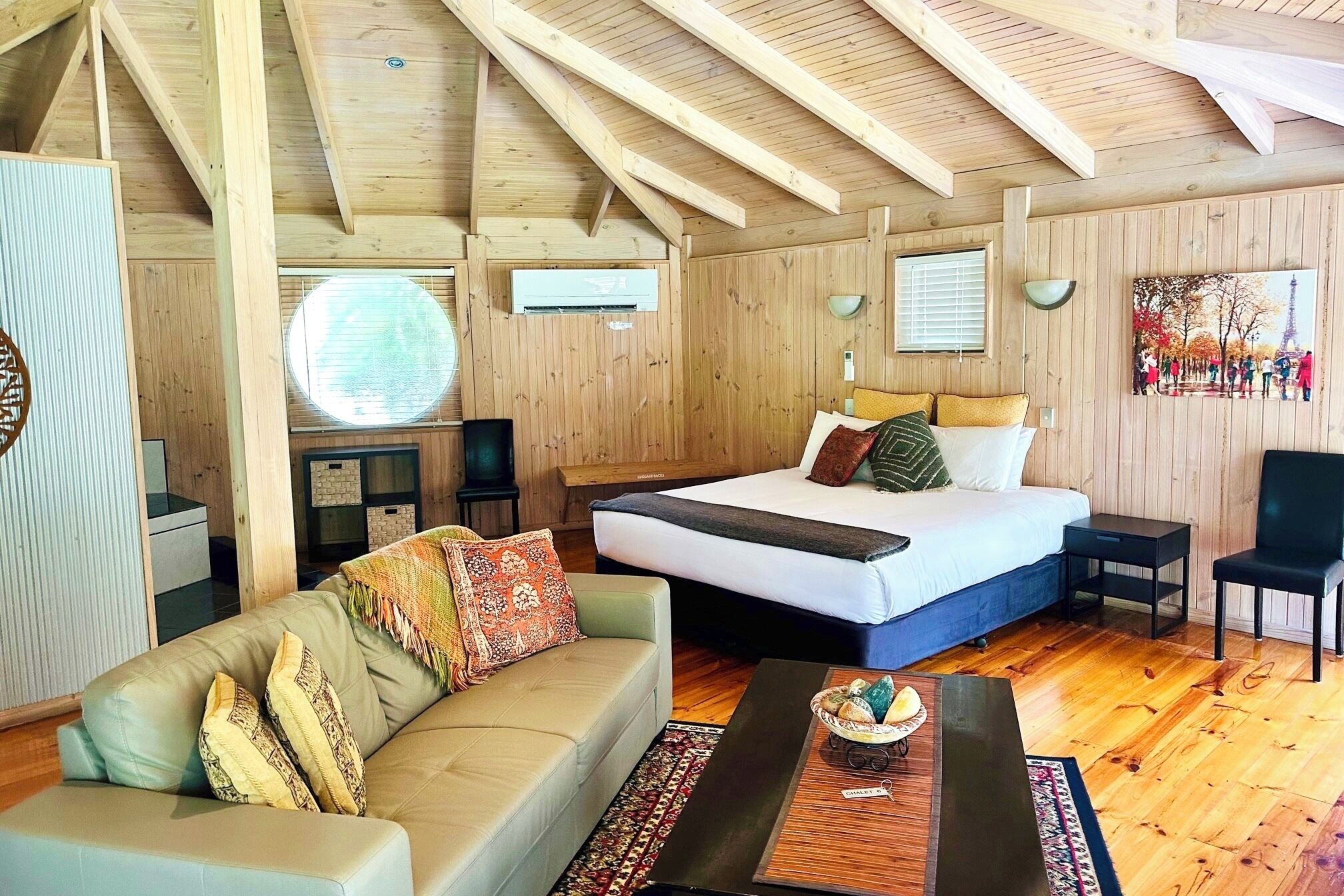 Um quarto aconchegante com uma cama, um sofá, uma mesa pequena e uma cadeira.