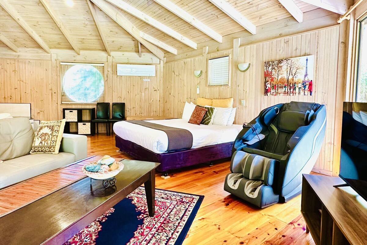 Um quarto aconchegante com uma cama, um sofá, uma cadeira de massagem e uma mesa de centro.
