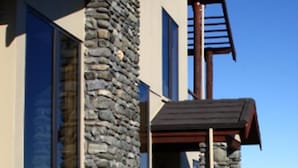 Uma casa moderna com chaminé de pedra, janelas amplas e um deck de madeira.