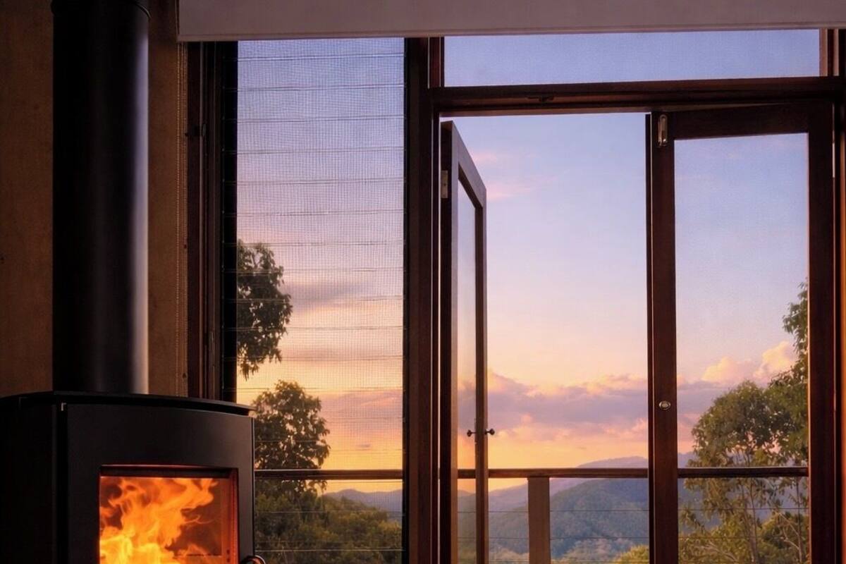 Quarto com lareira a lenha e porta de vidro deslizante para varanda com vista panorâmica.
