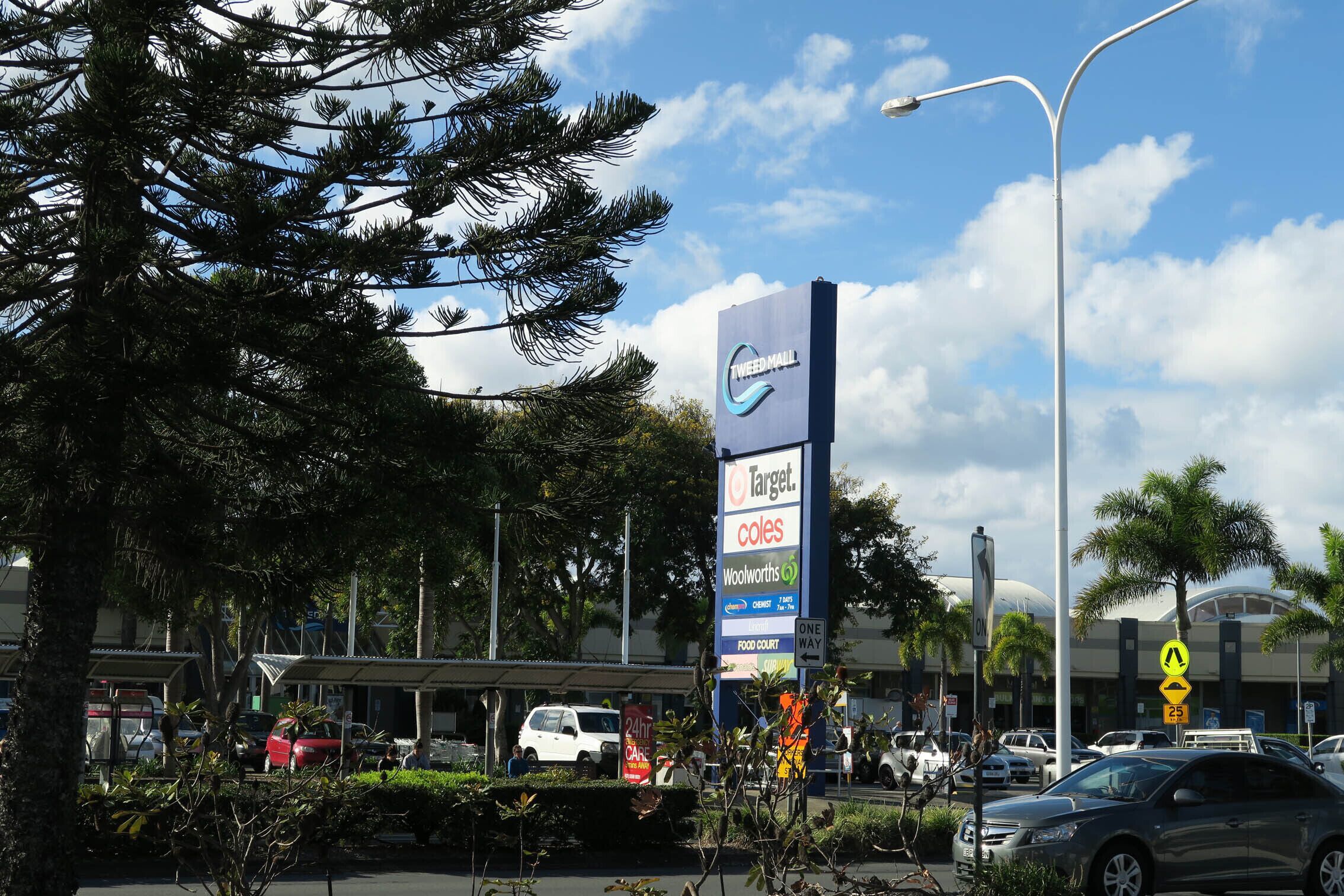 Uma área comercial com placas da Target e Woolworths, uma praça de alimentação e um estacionamento.
