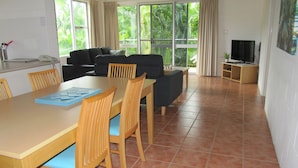 Uma sala ampla com mesa de jantar, cadeiras, sofá e televisão.