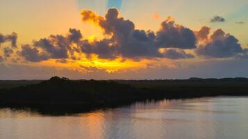 Um pôr do sol sobre águas tranquilas com o horizonte ao longe.