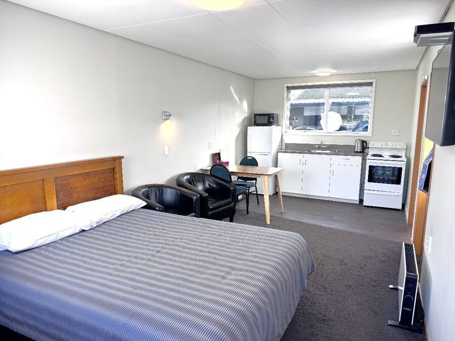 Quarto de hotel com cama, escrivaninha, micro-ondas, frigorífico e fogão.