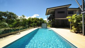Uma piscina retangular com água azul cristalina, rodeada por um deck de concreto.