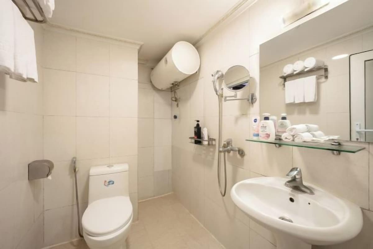 Uma casa de banho moderna com sanita, chuveiro e lavatório.