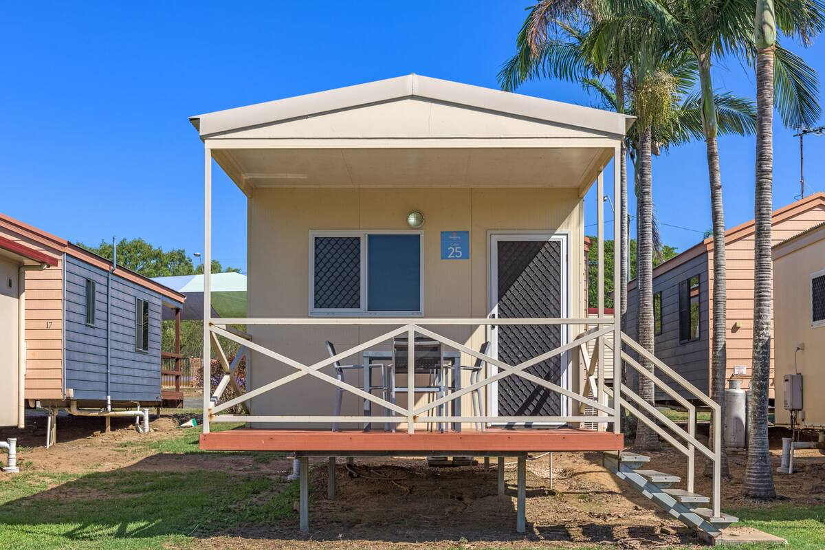 Um edifício térreo com telhado plano, uma varanda com grade e uma porta com o número 25.