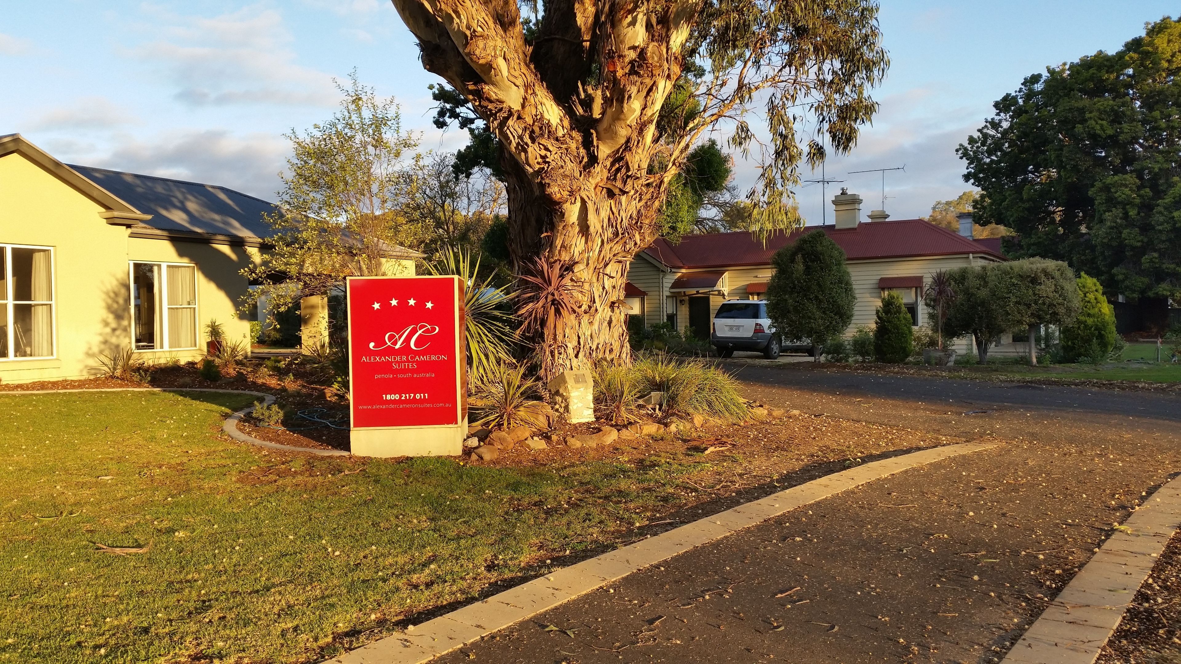 Placa vermelha do Alexander Cameron Suites em Penola, Austrália do Sul, com detalhes de contato e endereço de site.