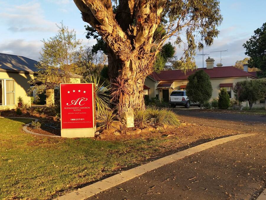 Placa vermelha do Alexander Cameron Suites em Penola, Austrália do Sul, com detalhes de contato e endereço de site.