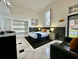 Quarto de hotel com cama, mesas de cabeceira, escrivaninha, cadeira e janela com vista.
