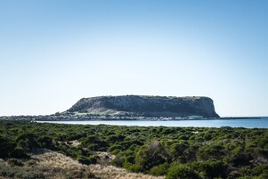 Paisagem costeira com uma colina imponente e um corpo de água.