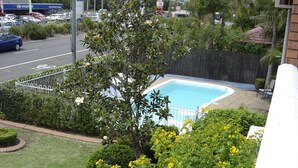 Bairro residencial com piscina, cercado por vegetação, e rua com carros estacionados.