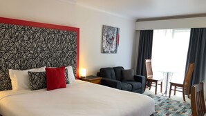 Quarto de hotel com uma cama grande, um sofá, uma mesa pequena e uma cadeira.