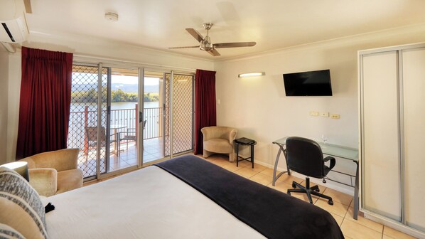 Quarto de hotel com cama, escrivaninha, cadeira, televisão e varanda com vista.