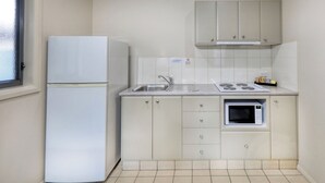 Uma cozinha compacta com geladeira embutida, pia, fogão e micro-ondas.